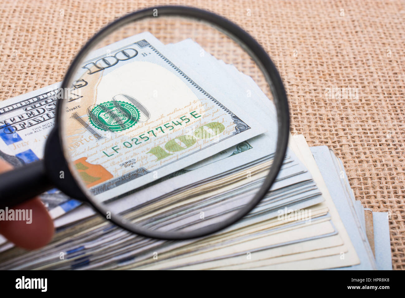 Magnifying glass is held over the banknote bundle of US dollar Stock ...