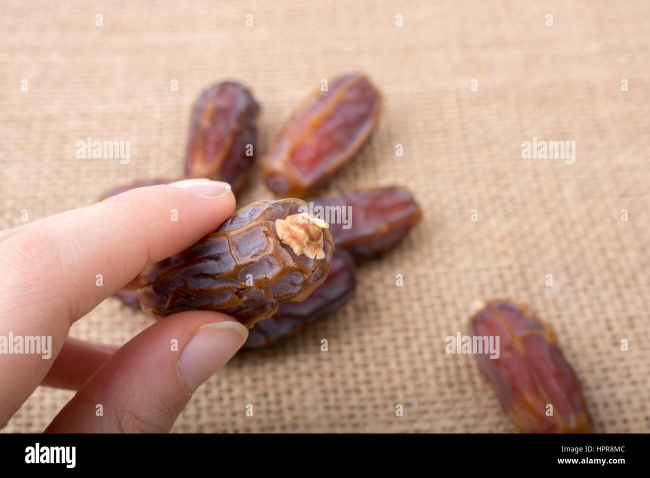 hand holding a date on a linen canvas background Stock Photo - Alamy