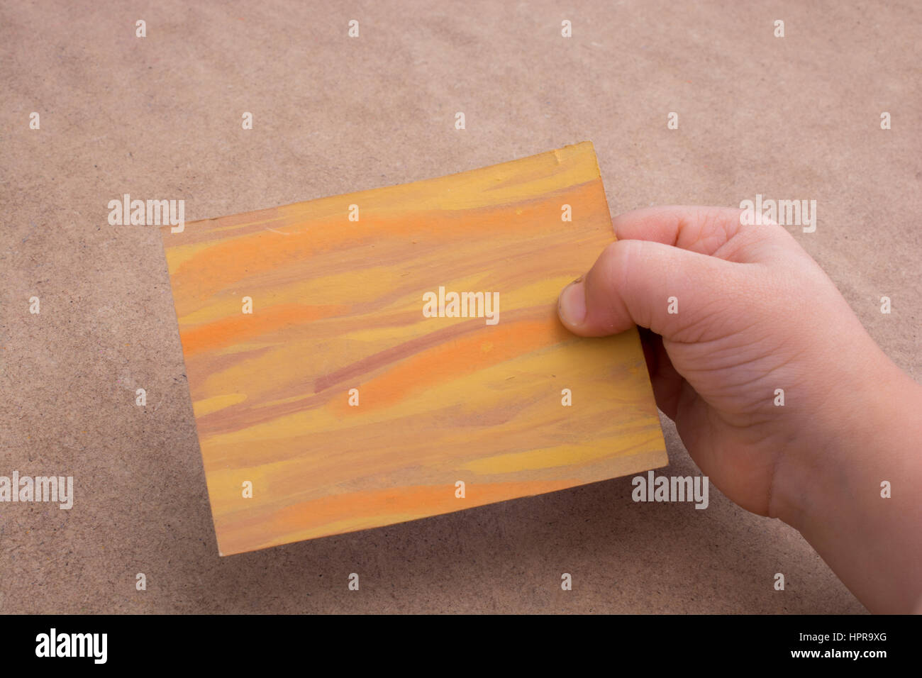 Hand holding painted note paper on brown background Stock Photo - Alamy