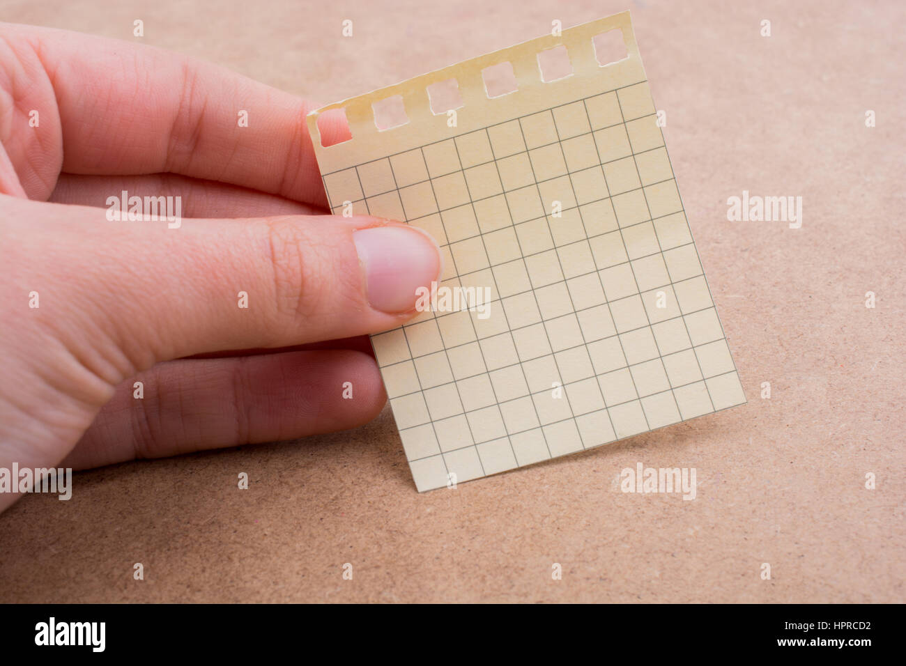 Hand holding a note paper on a brown background Stock Photo - Alamy