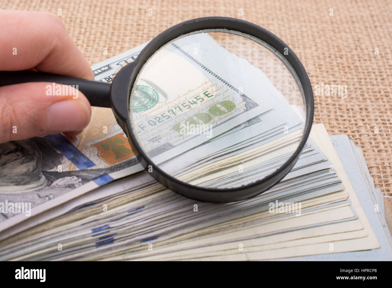 Magnifying glass is held over the banknote bundle of US dollar Stock ...