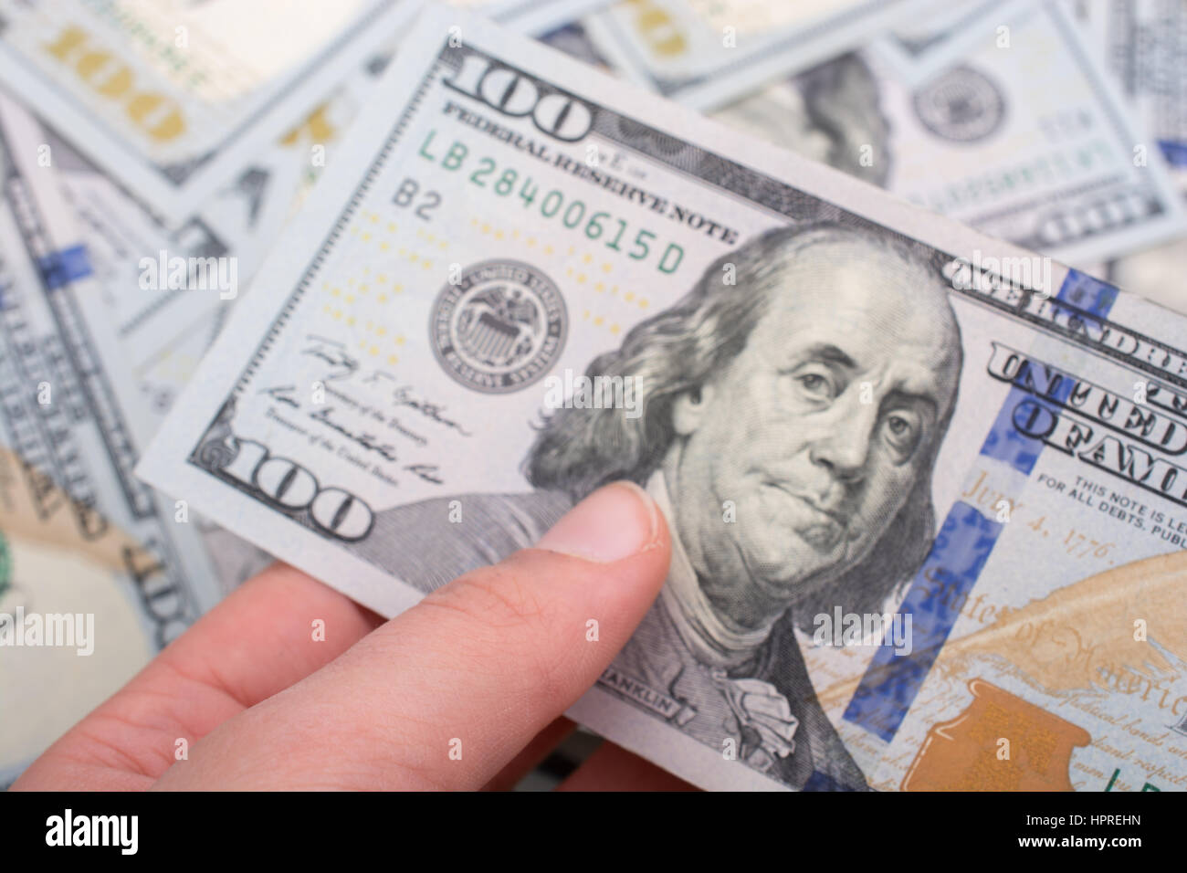 Hand holding banknotes on other banknotes of US dollar spread around ...