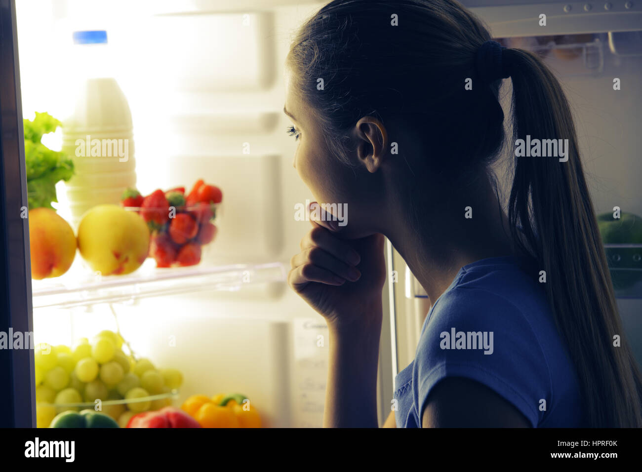 Young woman craving food choosing near refrigerator at night Stock ...