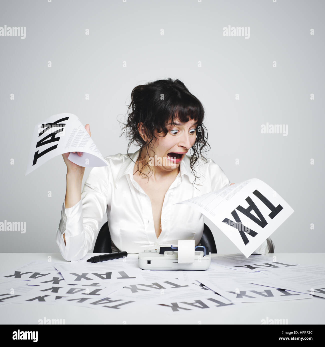 Very surprised woman at her desk looking at terrible tax bills Stock ...