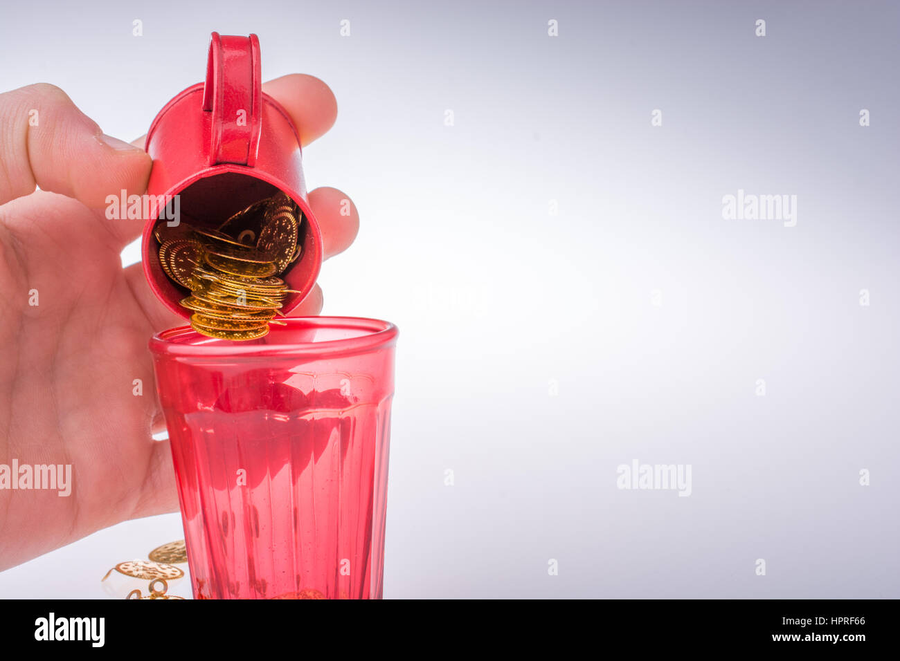 Hand puring gold coins into a glass on a white background Stock Photo ...