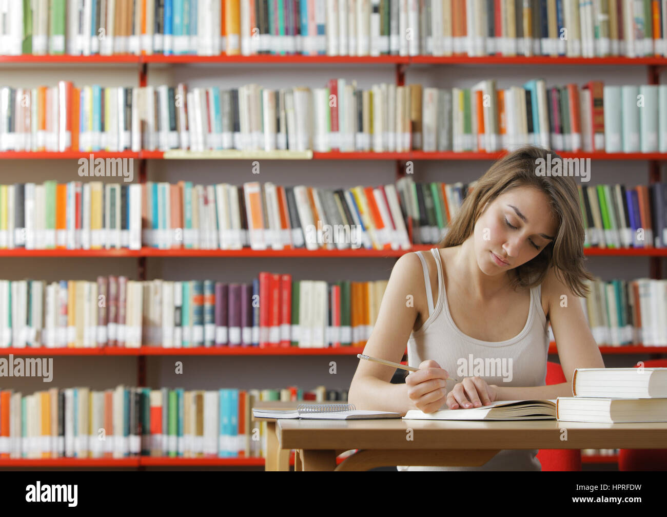 Portrait of a serious young student reading a book in a library Stock ...
