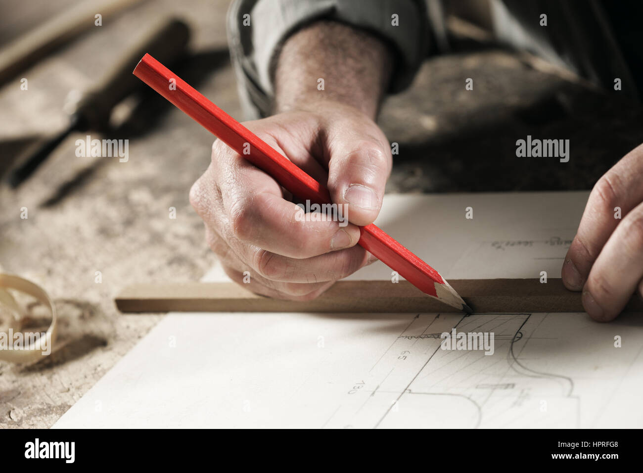 Closeup view of a carpenter using a red pencil to draw a line on a ...