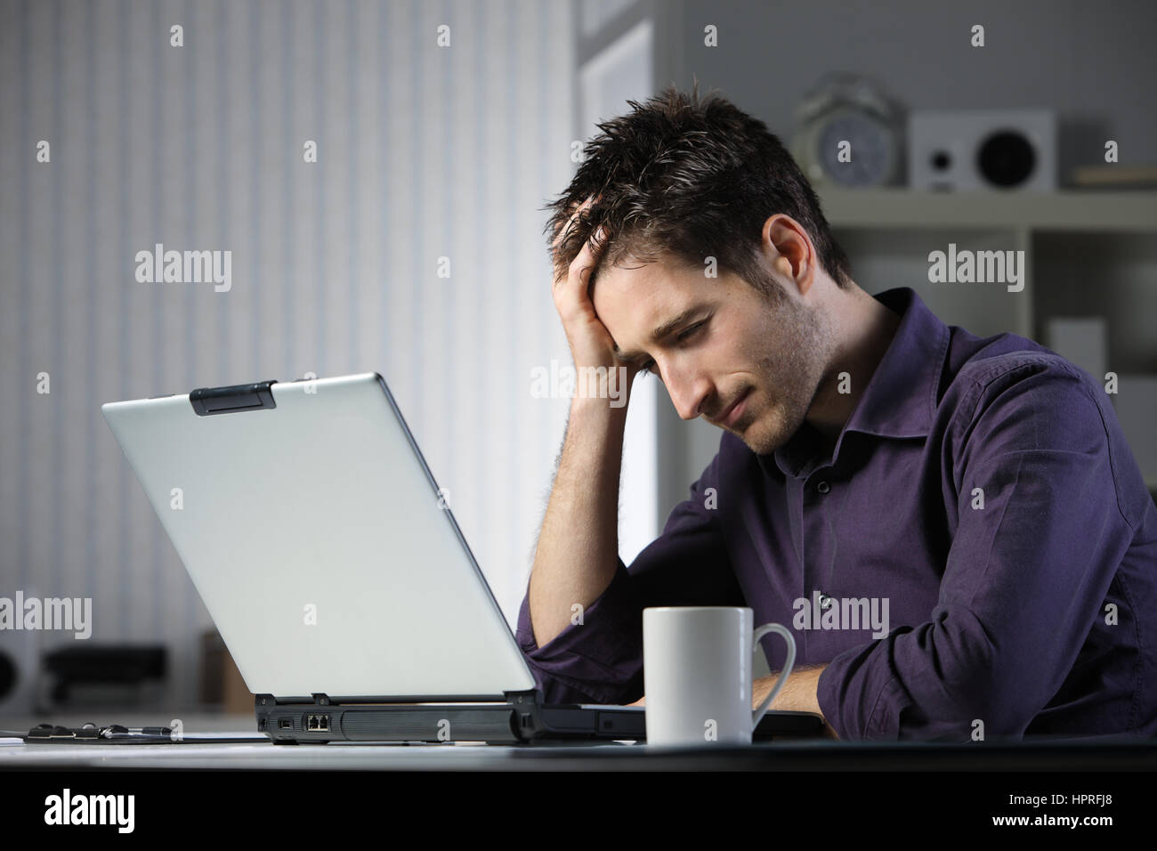 Unhappy stressed male student looking at his laptop computer with his ...