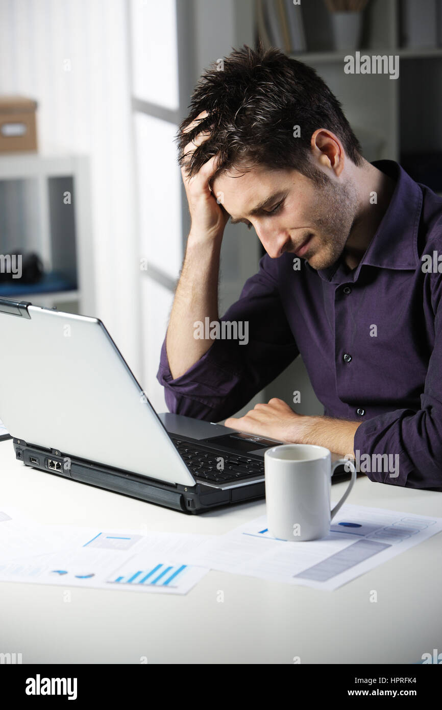 Stressful young man working on laptop Stock Photo - Alamy