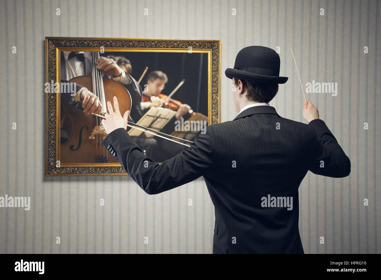 Male orchestra conductor directing with his baton in concert ...