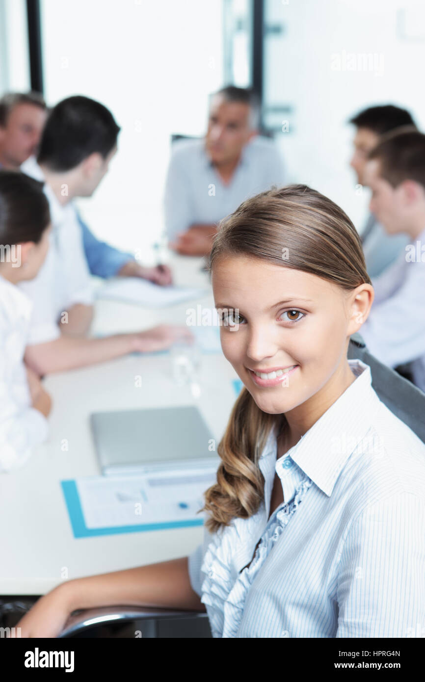 Portrait of a pretty young executive with her team in the background ...