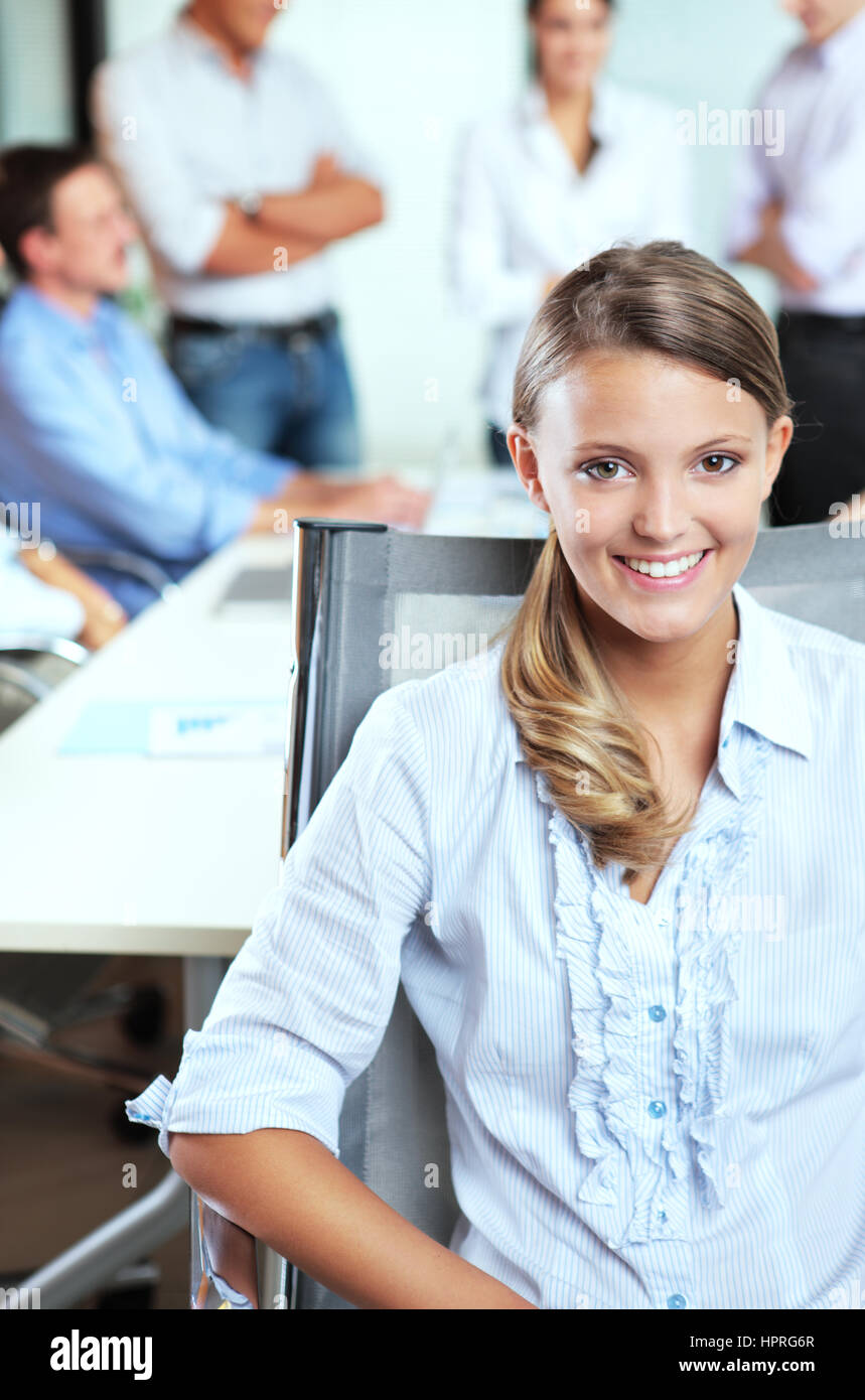 Portrait of a pretty young executive with her team in the background ...