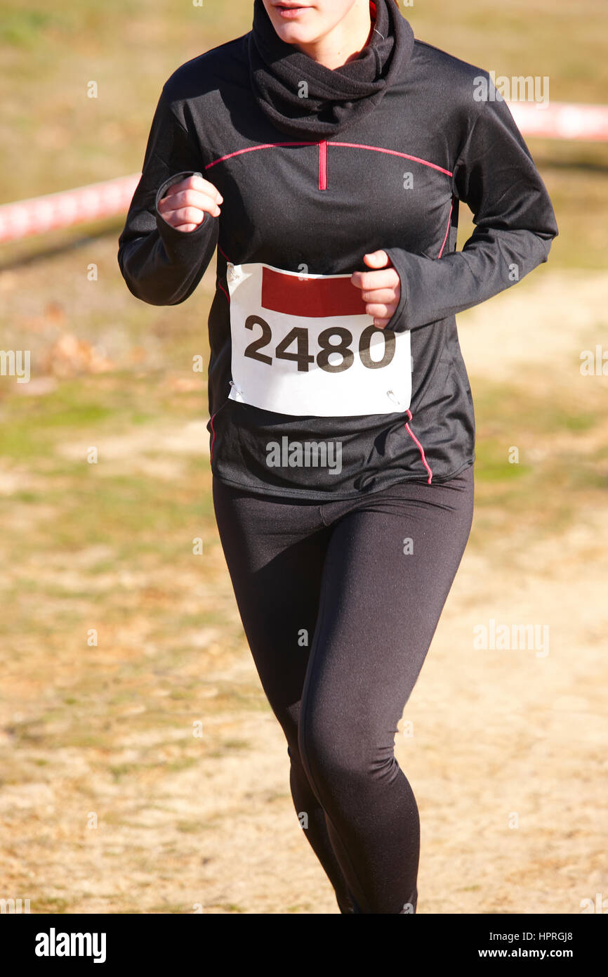 Female athletic runner on a cross country race. Outdoor circuit ...