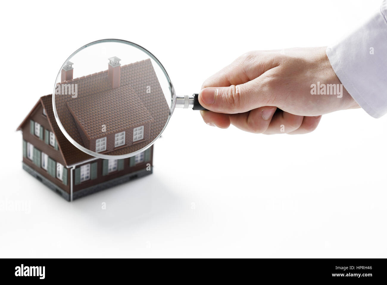 Concept image of a home inspection. A male hand holds a magnifying ...