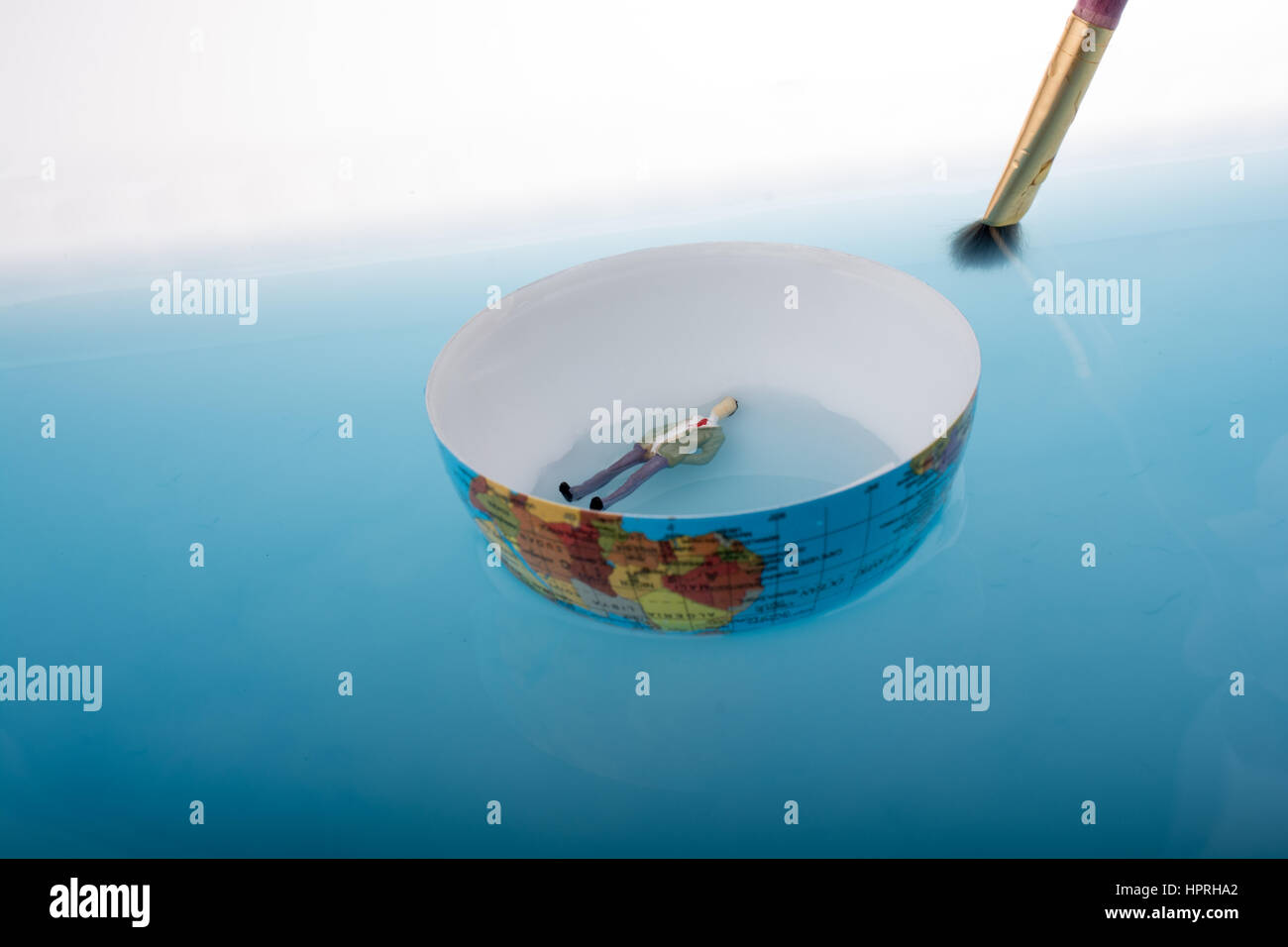 Little model globe with figurine floating in blue water Stock Photo - Alamy