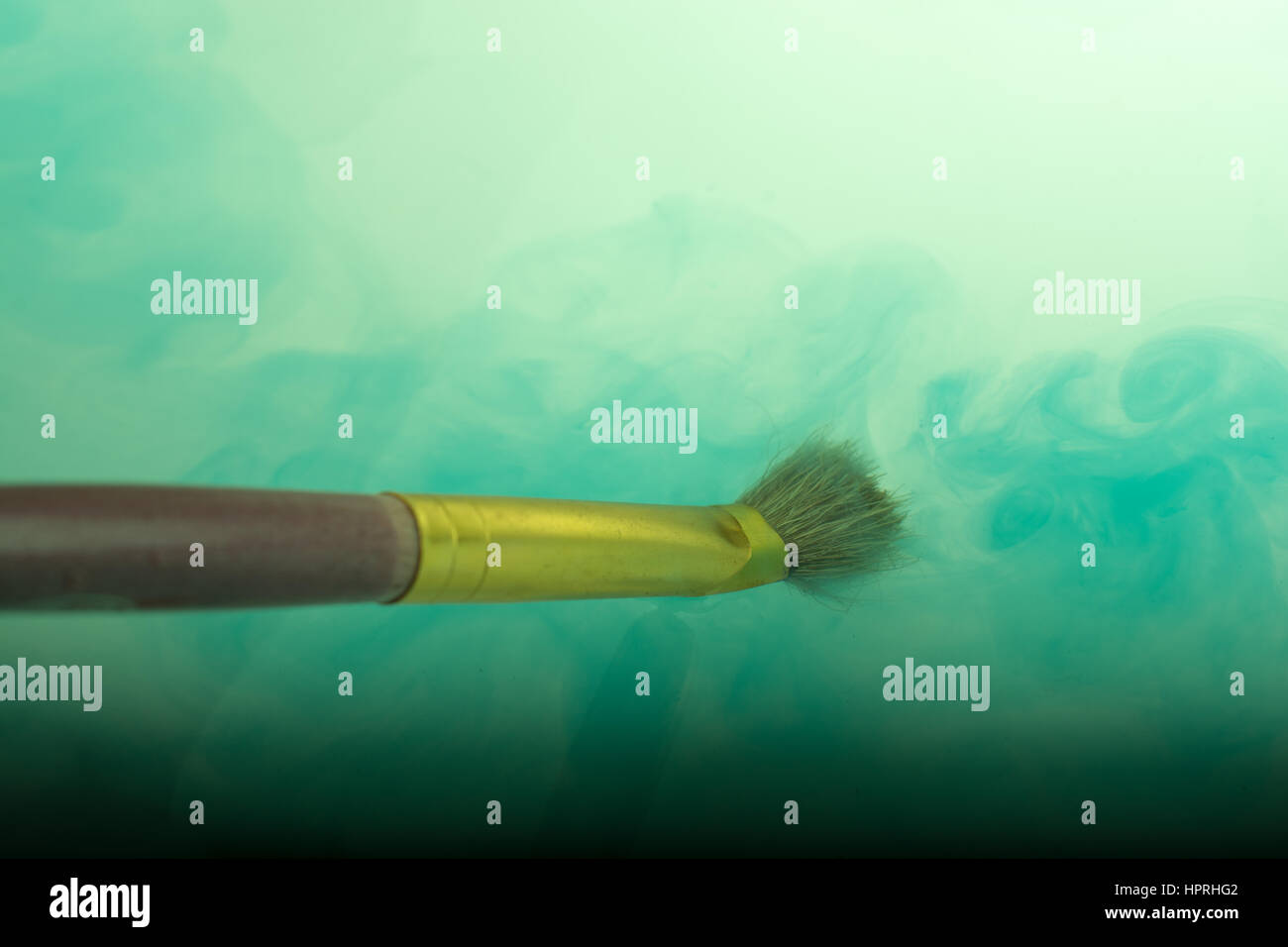 Watercolor paint dissolving in water as painting brush touches water ...