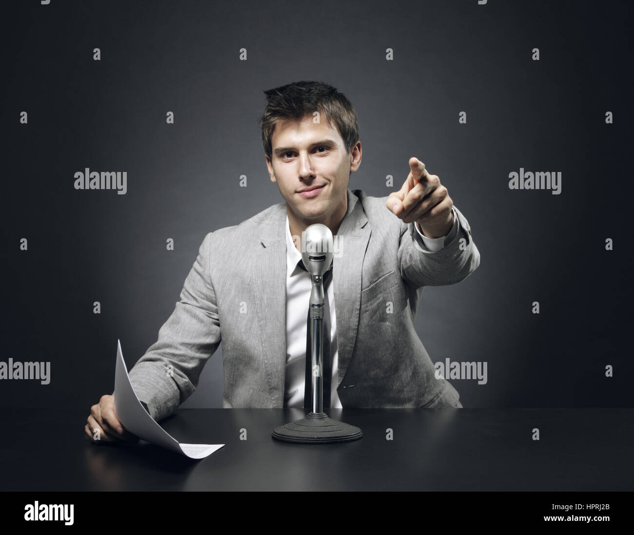 Anchorman smiling, reads the new and points the finger at the camera ...