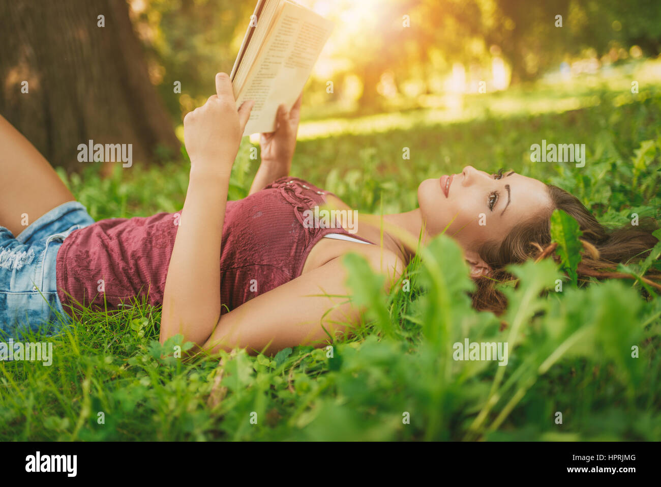 Beautiful pensive girl lying in grass and reading book Stock Photo - Alamy Beautiful pensive girl lying in grass and reading book Stock Photo - Alamy