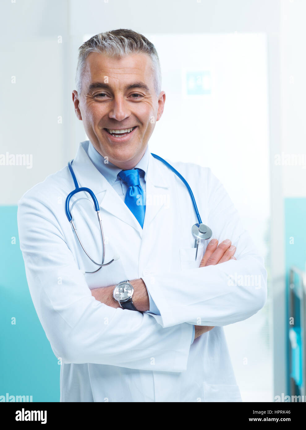 Friendly doctor portrait with arms crossed and medical equipment in teh ...