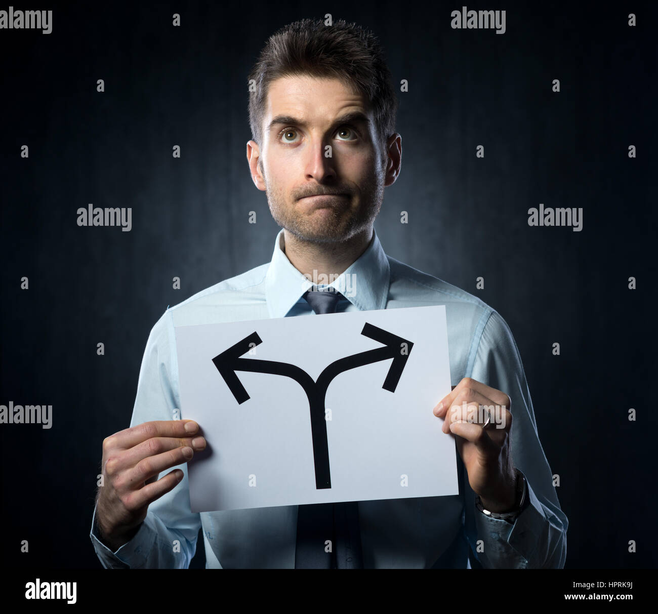 Man holding a sign with directions and pensive expression Stock Photo ...