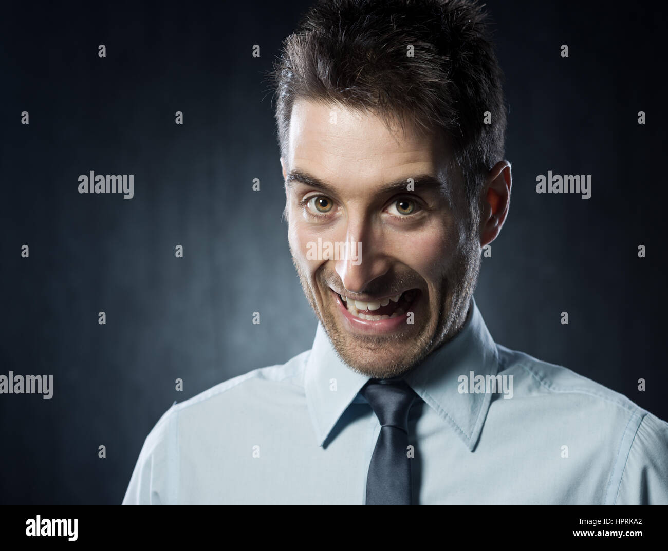 Young happy business man with funny expression on dark background Stock ...