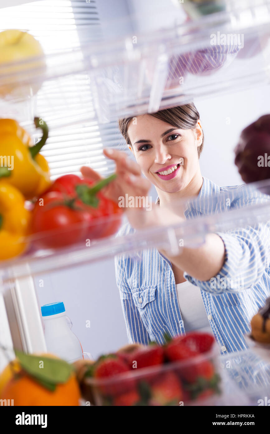 Young woman taking fresh healthy vegetables from refrigerator Stock ...