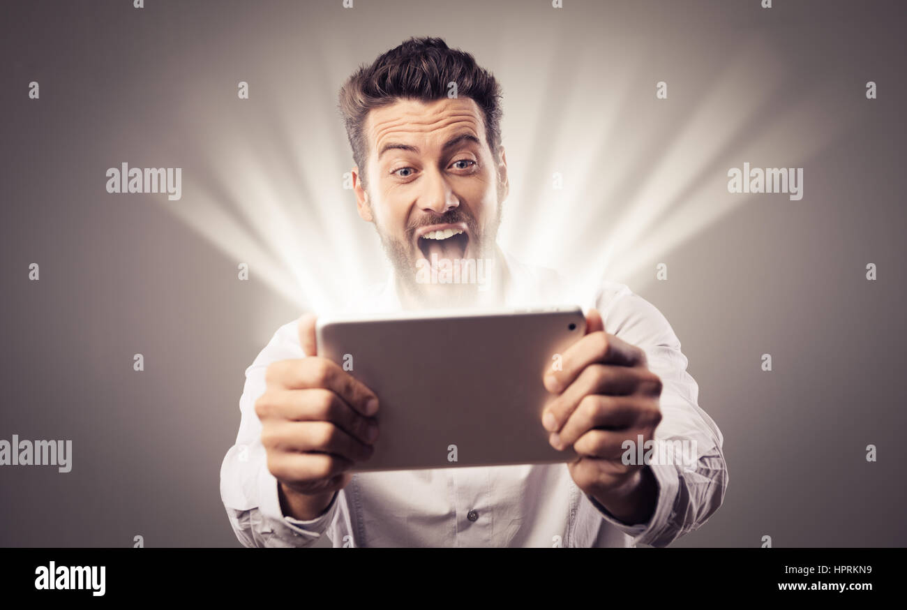 Cheerful smiling man watching videos and playing video games on his ...