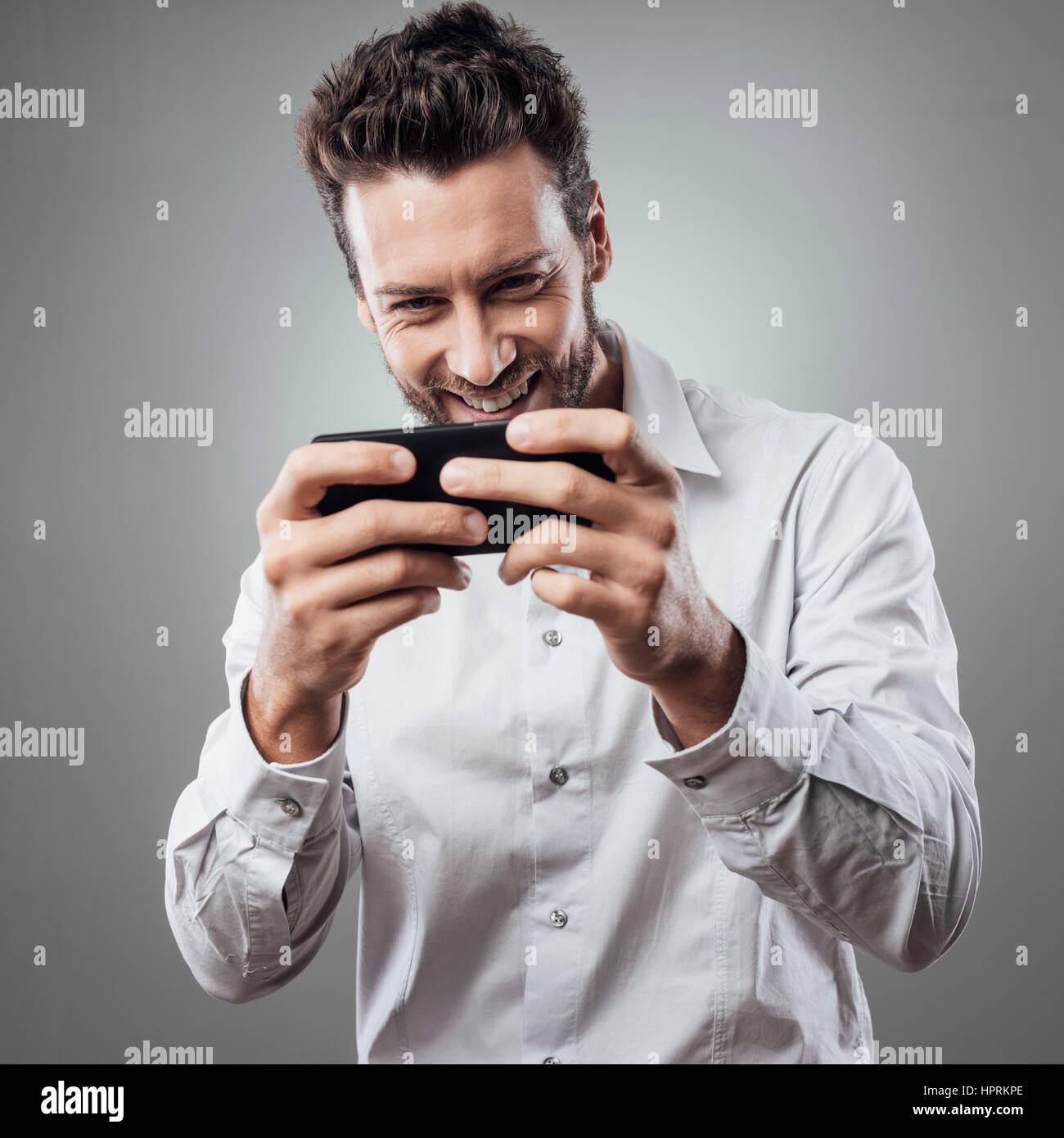 Handsome young man playing with his smartphone Stock Photo - Alamy