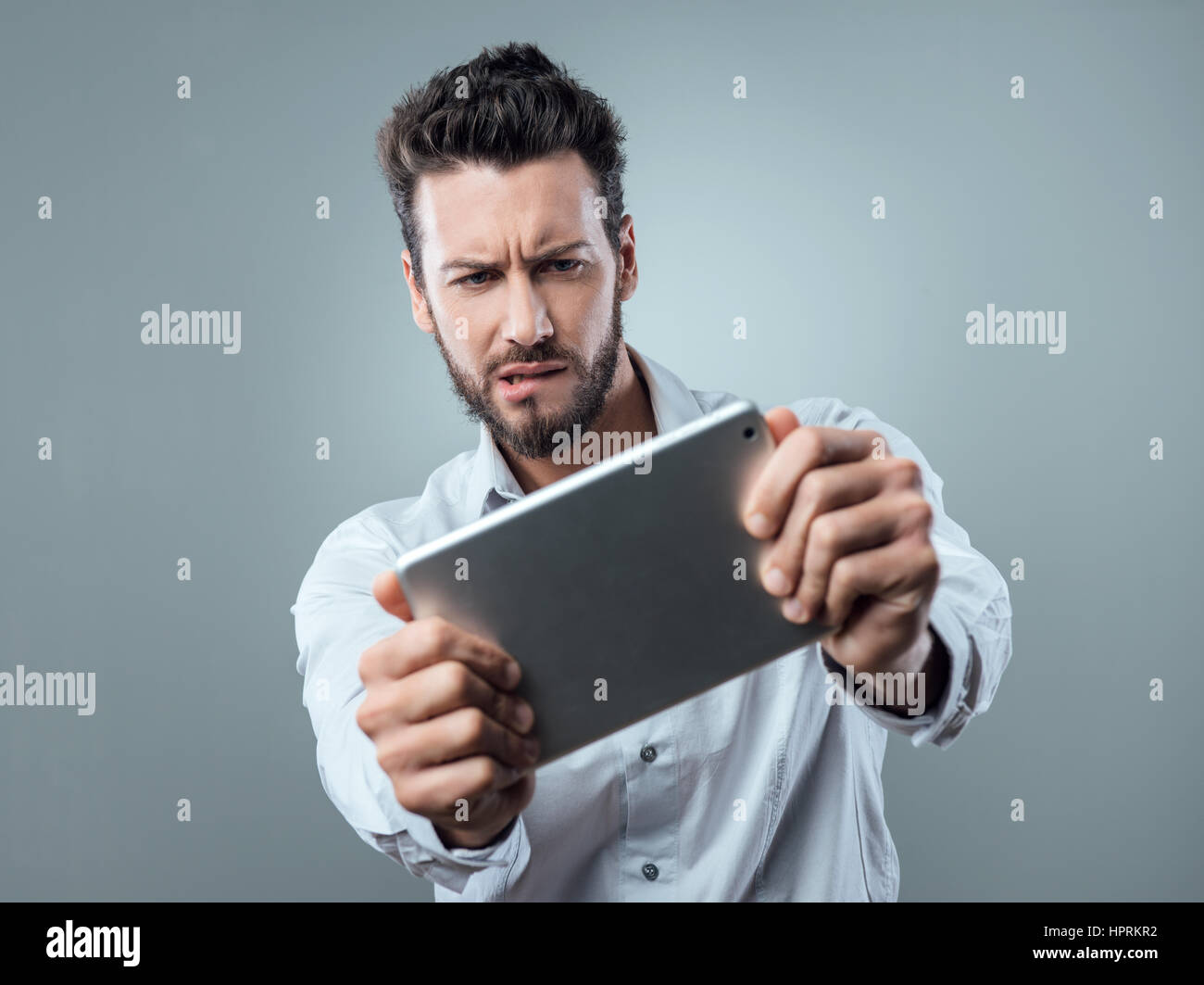 Confused man biting his lip and watching a digital tablet Stock Photo ...