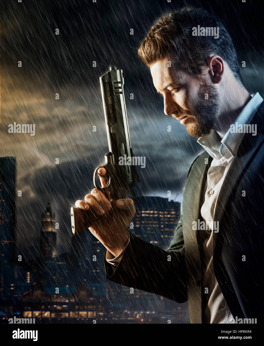 Brave handsome male agent under pouring rain holding a gun, city ...