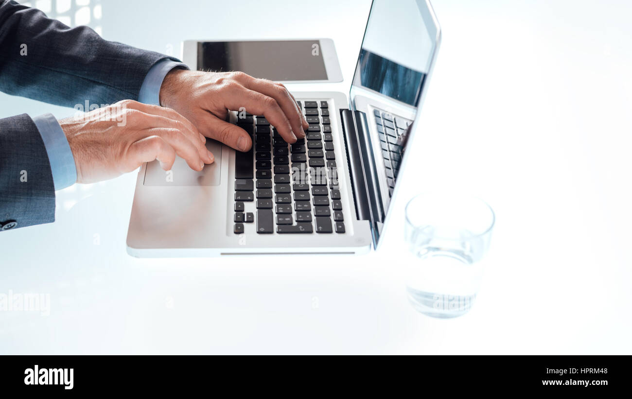 Professional businessman sitting at office desk and working with laptop ...