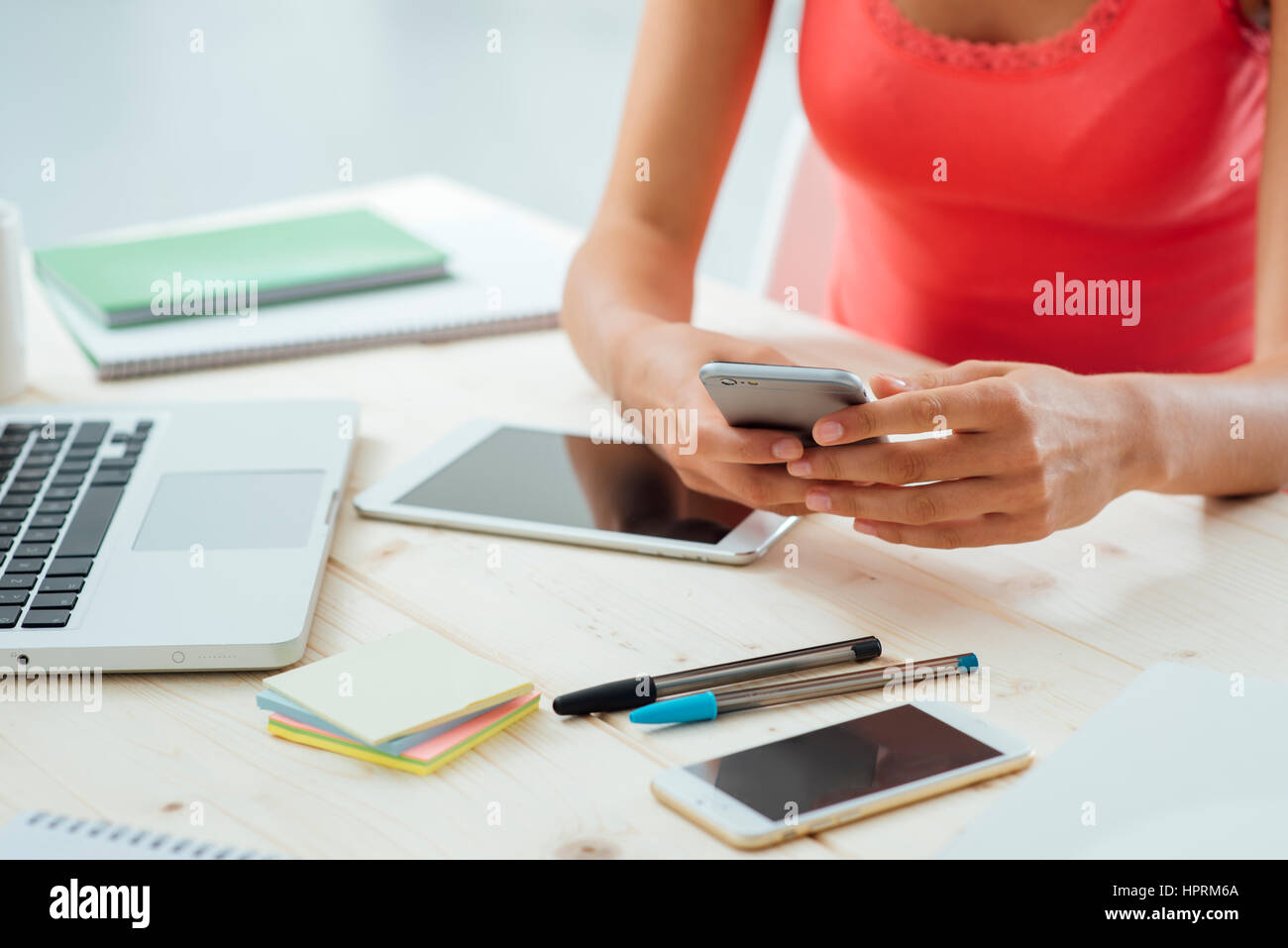 Teen girl sitting at desk and texting with her mobile touch screen ...