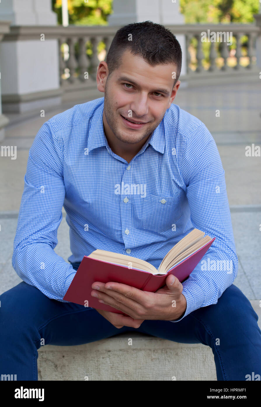Picture of a handsome man reading an interesting book Stock Photo - Alamy
