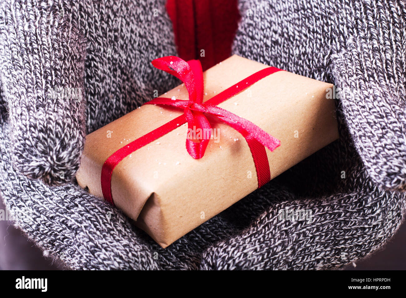 Open hands holding a present wrapped in a red ribbon Stock Photo - Alamy