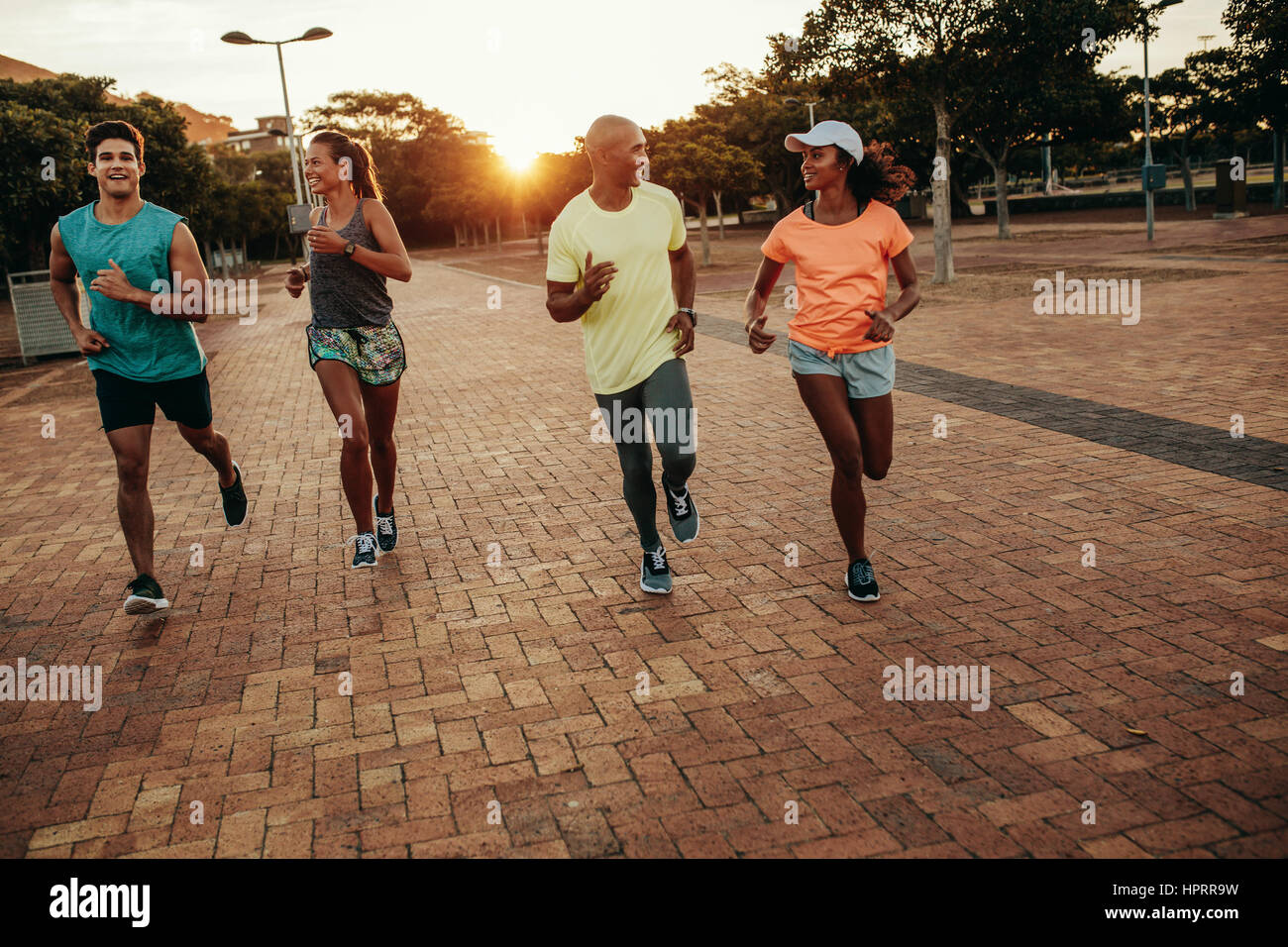 Young people running together at the park. Runners training outdoors in ...
