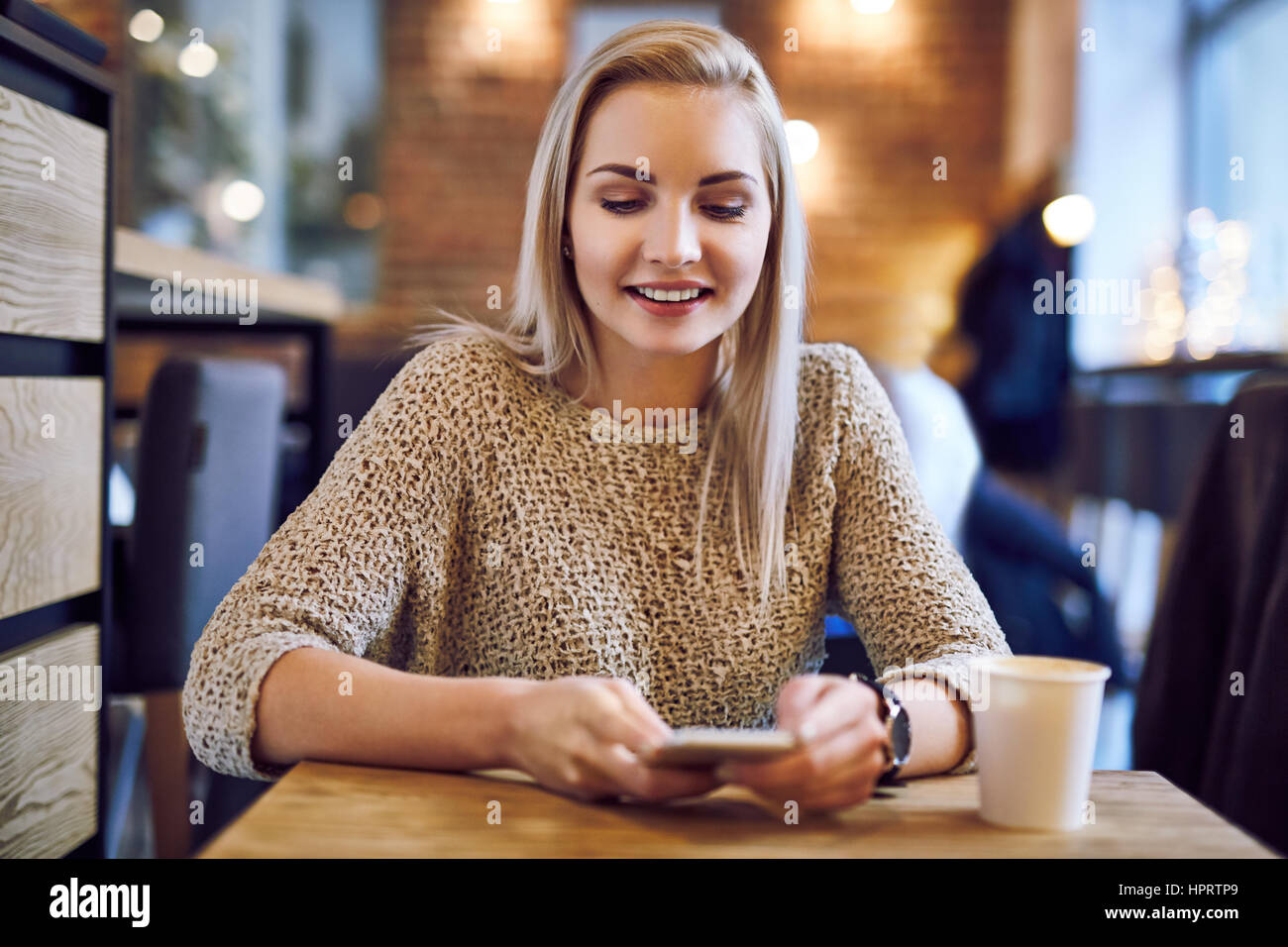 Happy young woman texting on her mobile phone sitting in a cafe Stock ...