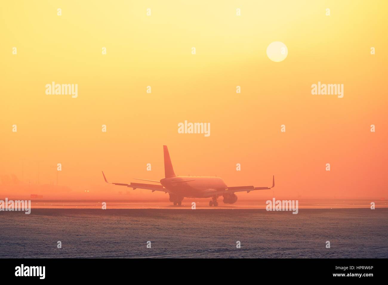 Freezing fog at the airport. Airplane landing during golden sunset ...