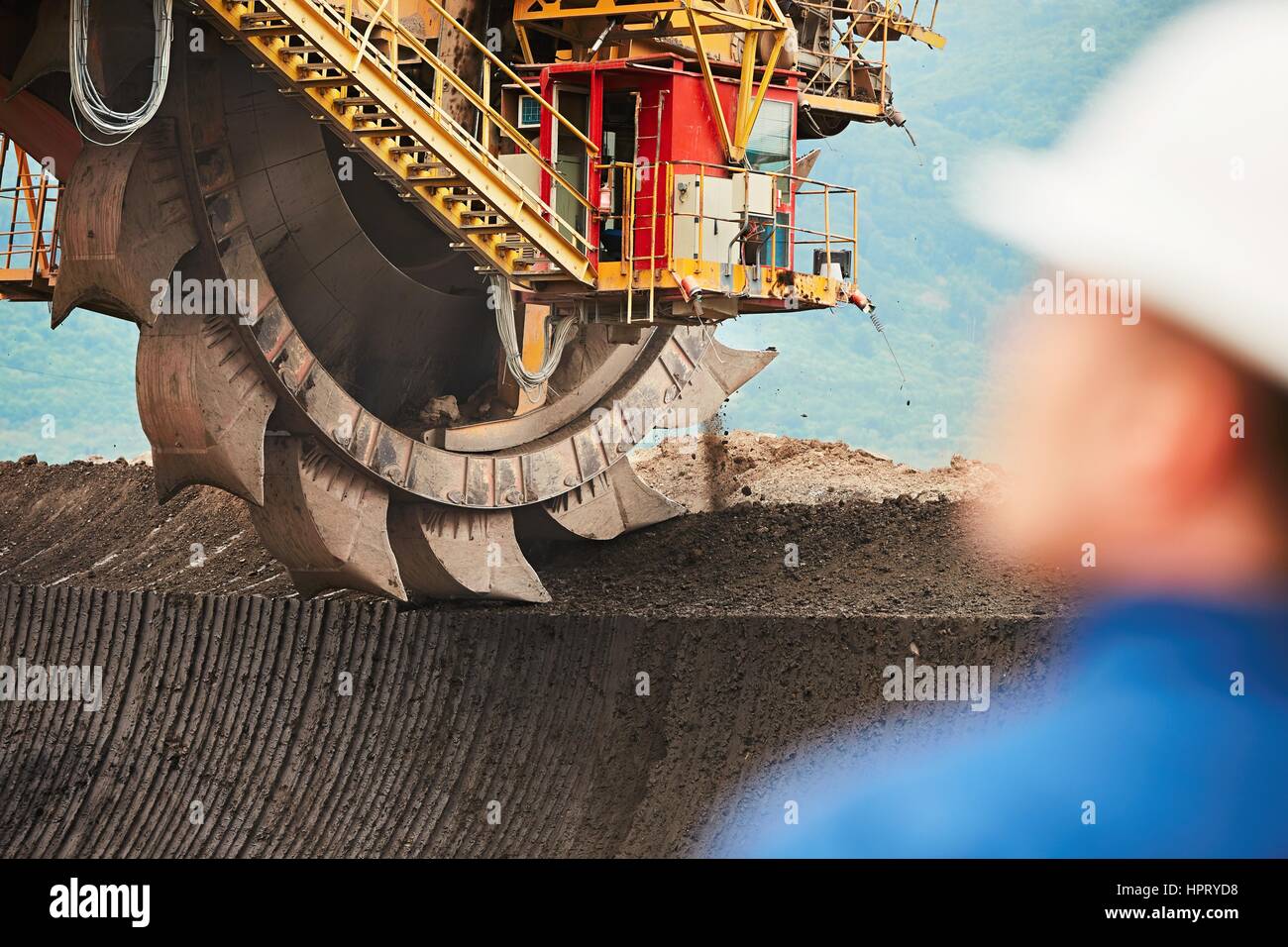 Coal mining in an open pit - Worker is looking on the huge excavator ...