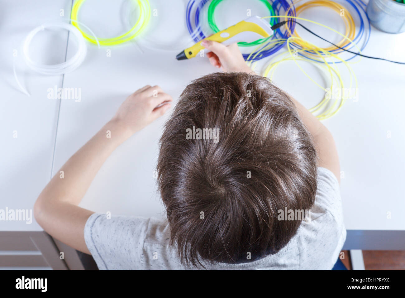 Happy child creating with 3D printing pen. Kid making new item ...