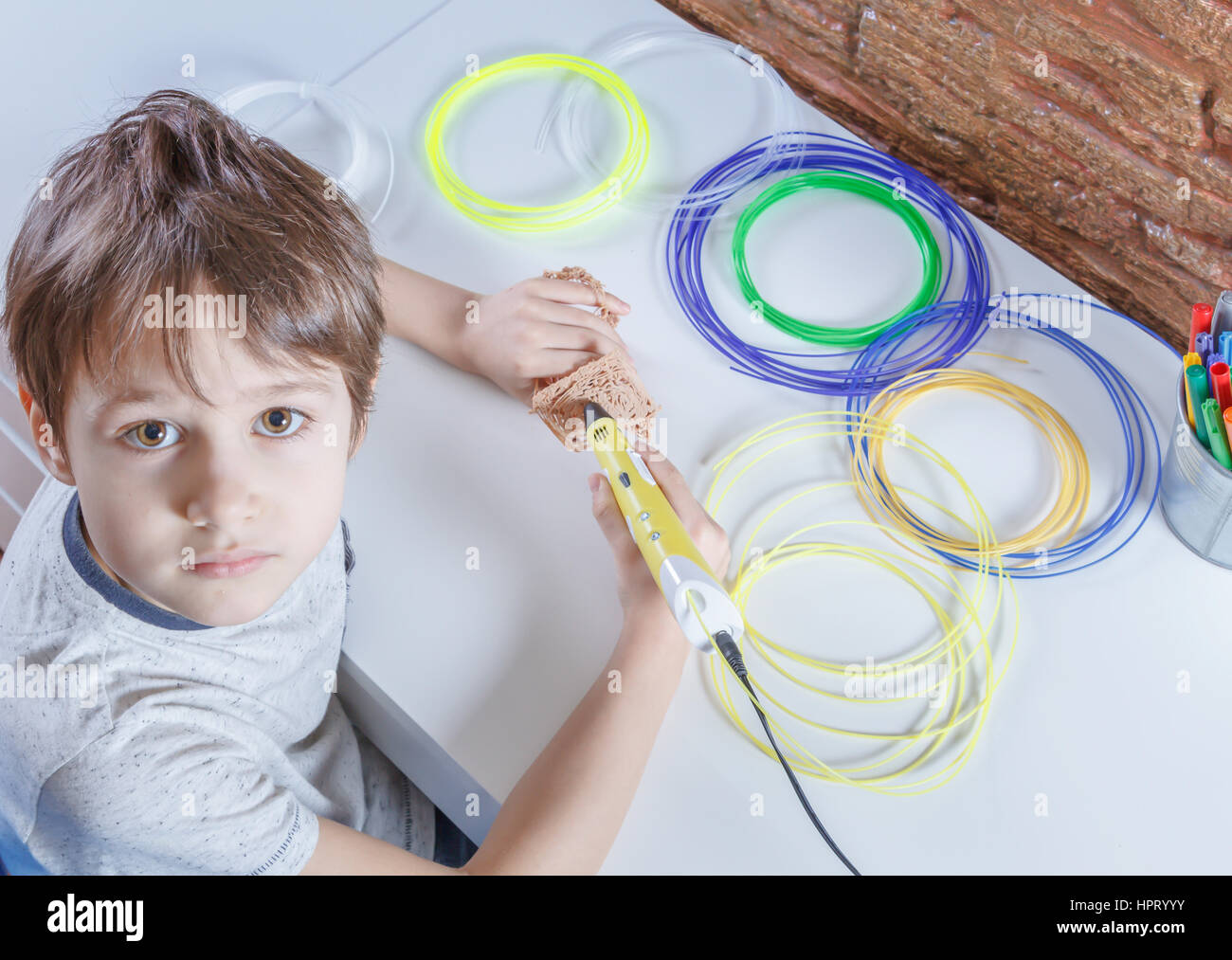 Happy child creating with 3D printing pen. Kid making new item ...
