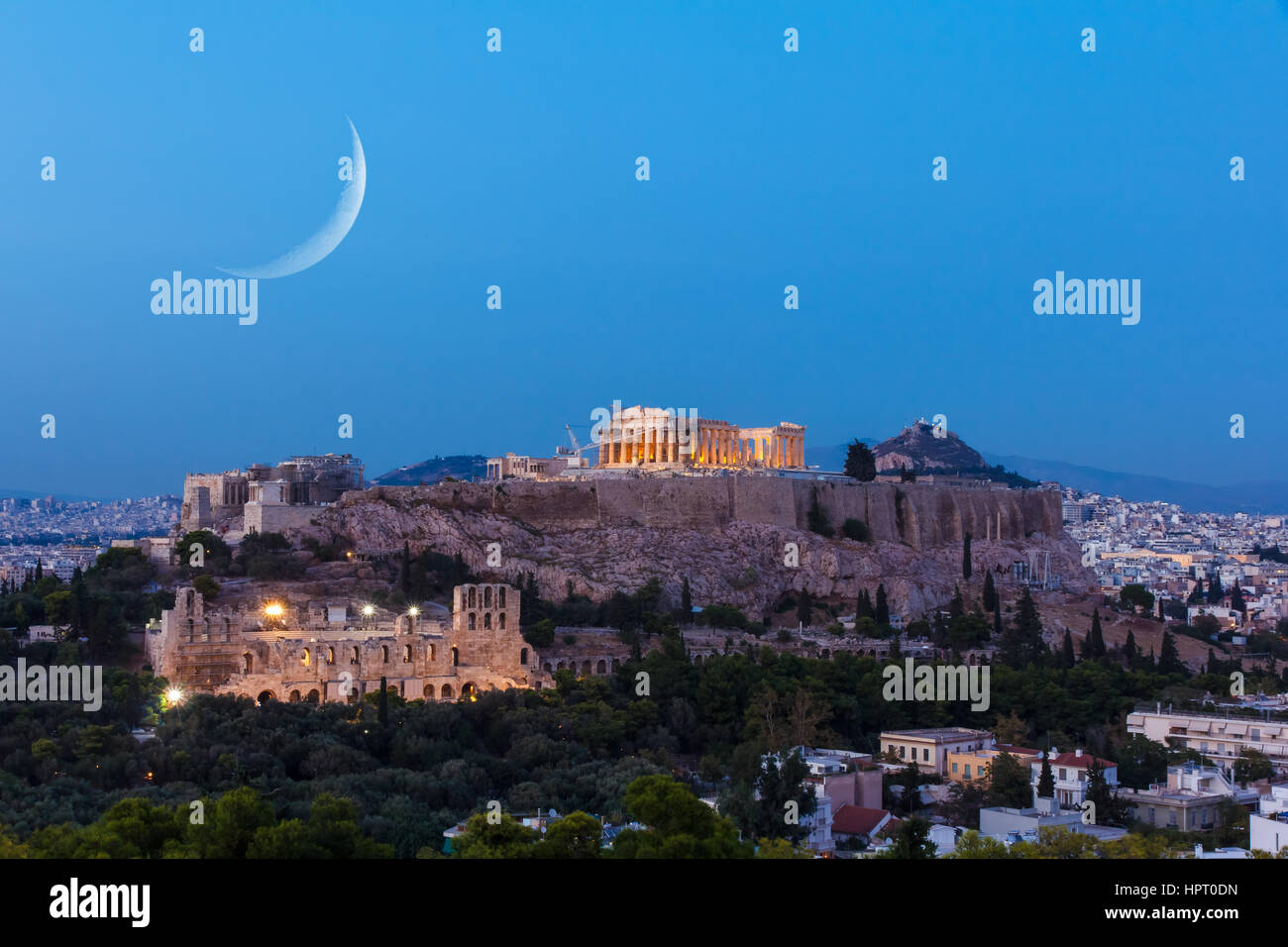 The Parthenon in Acropolis Hill in Athens, Greece shot in blue hour with the moon rising above ...