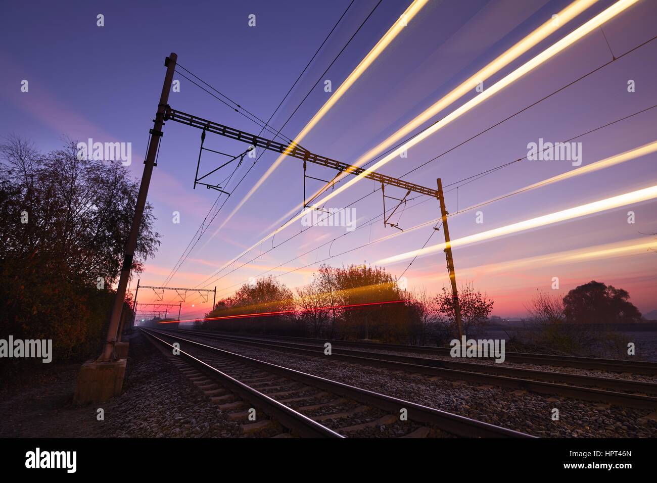Passenger train on railroad tracks at the sunrise - blurred motion ...