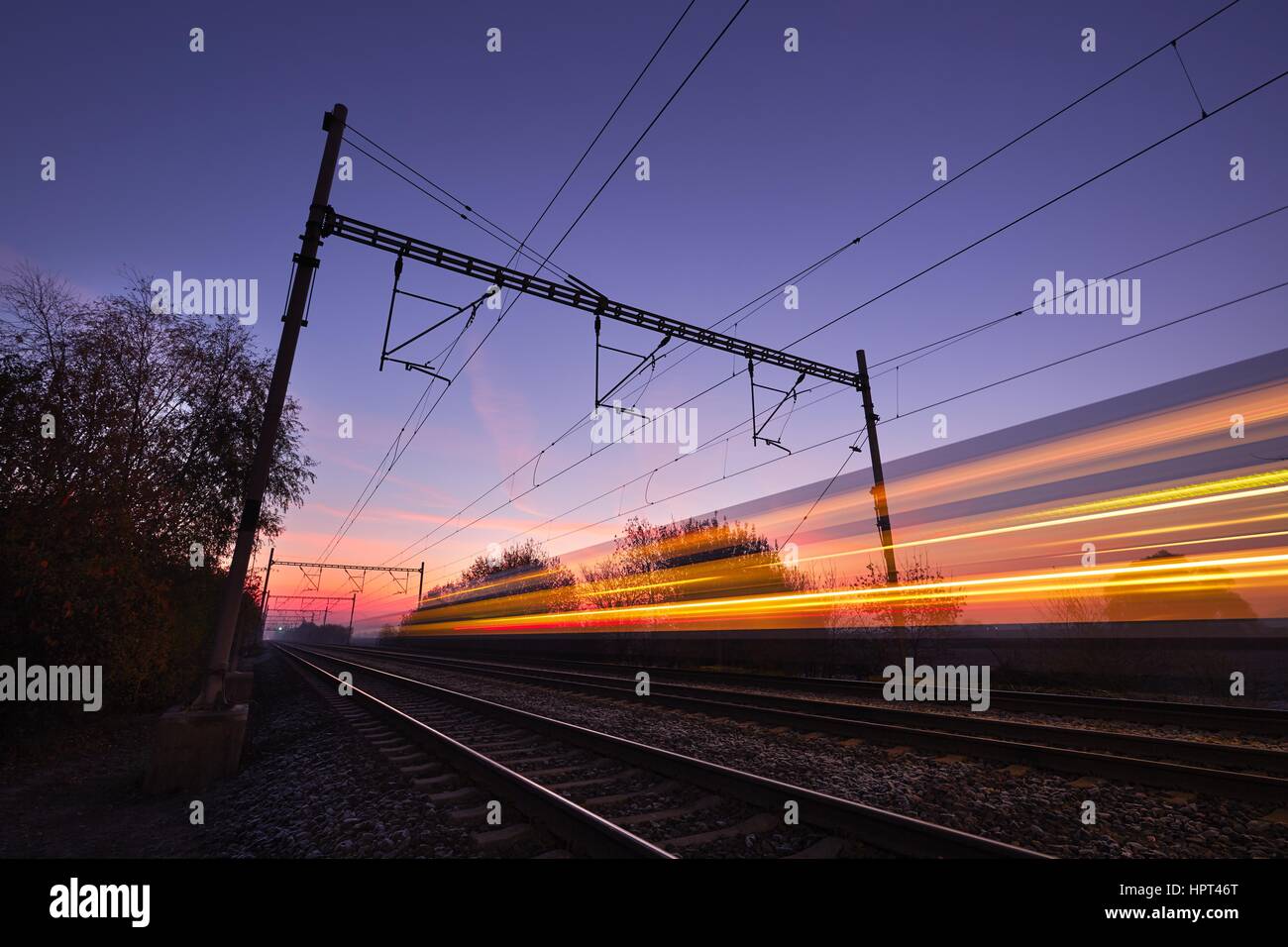 Passenger train on railroad tracks at the sunrise - blurred motion ...