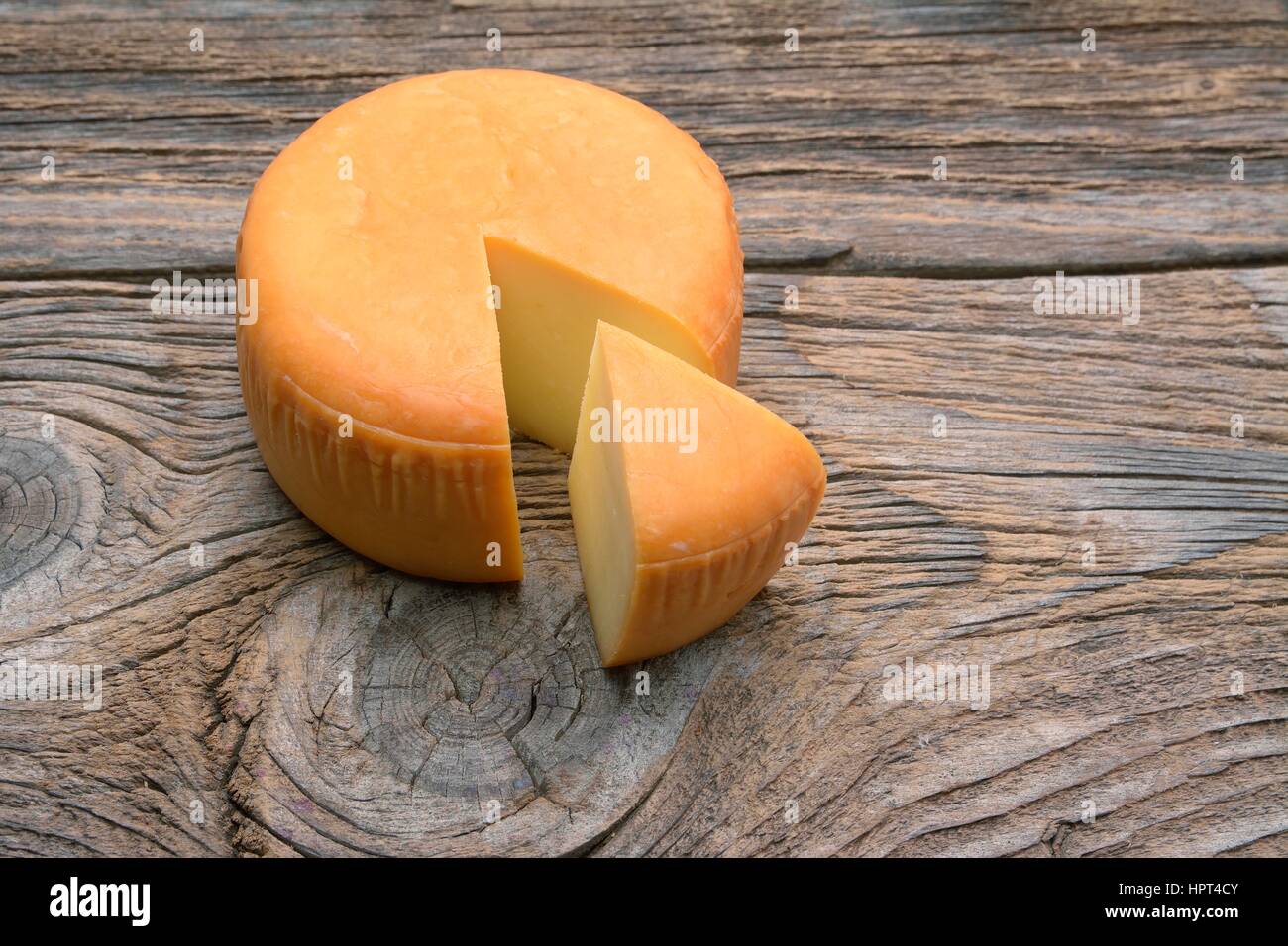 Cheese wheel on wooden table Stock Photo - Alamy