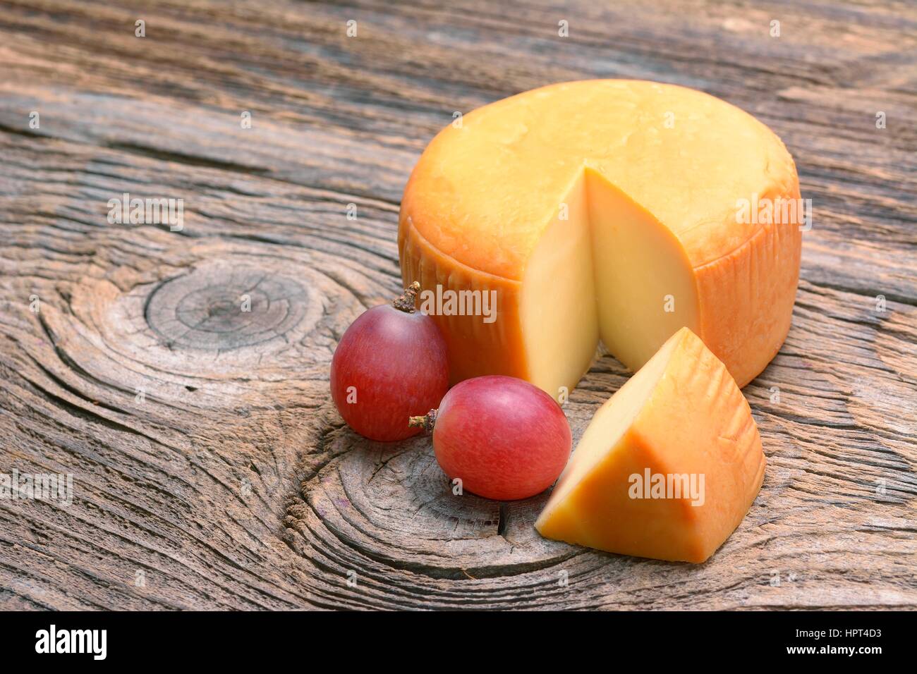 Cheese wheel on wooden table Stock Photo - Alamy