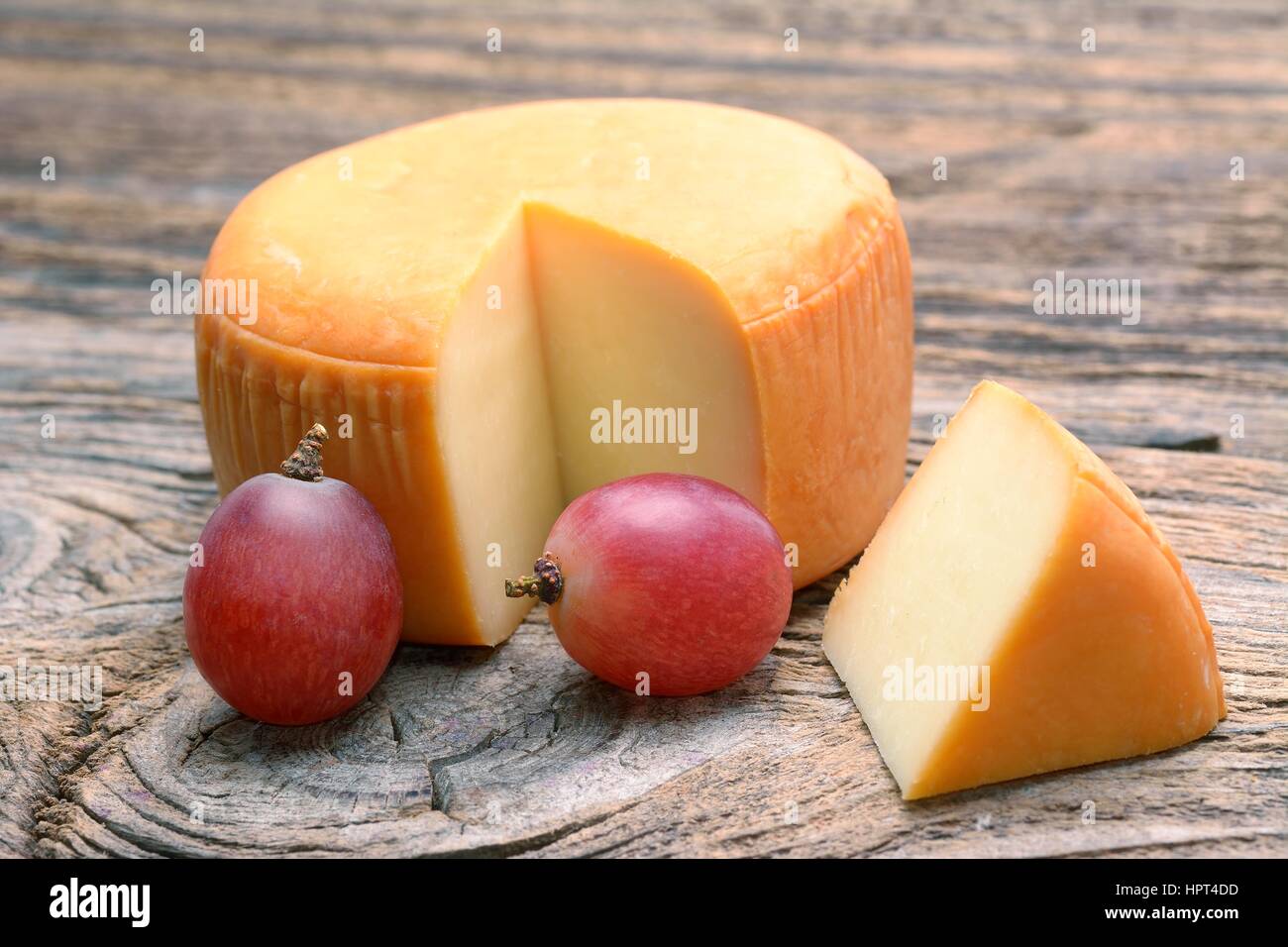 Cheese wheel on wooden table Stock Photo - Alamy