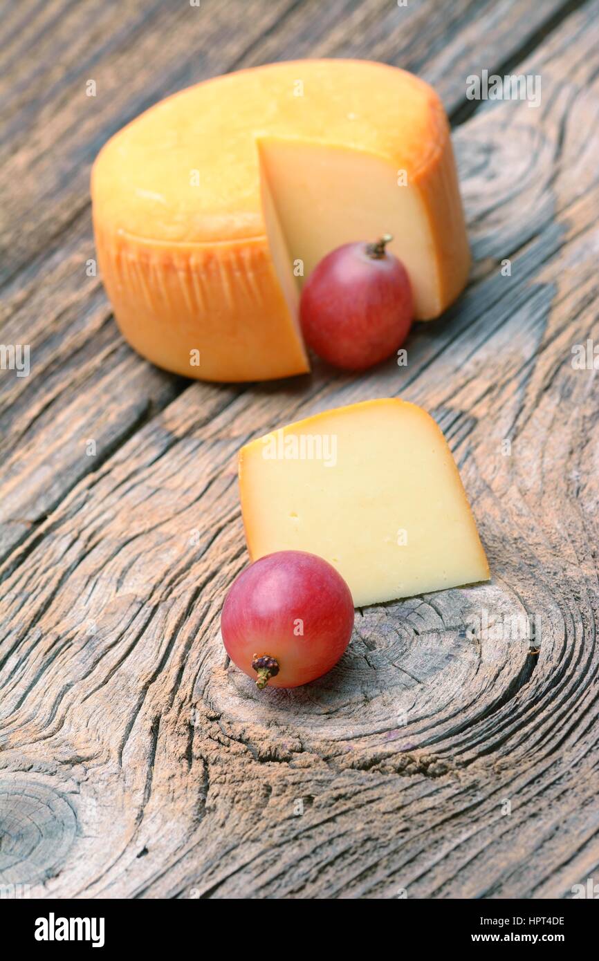 Cheese wheel on wooden table Stock Photo - Alamy