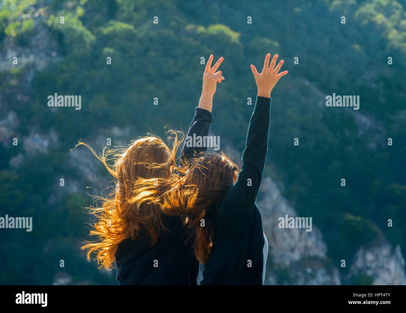 Two young women with hands raised enjoy the wind in the early summer ...
