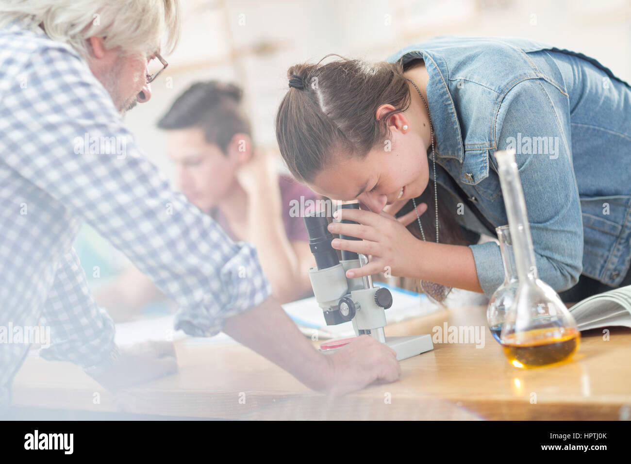 Science student with teacher in class looking through microscope Stock ...