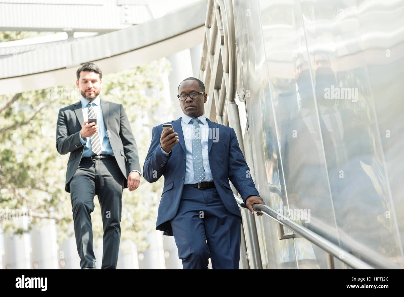 Two businessmen on the move looking at cell phones Stock Photo - Alamy